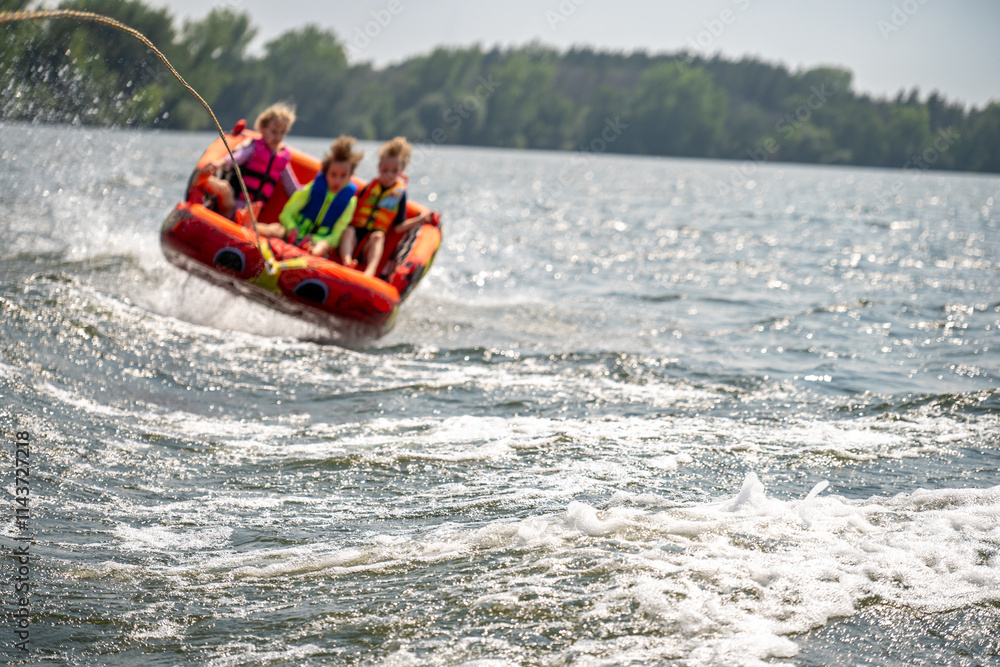 Inflatable raft being pulled at a high speed by a boat in a ...