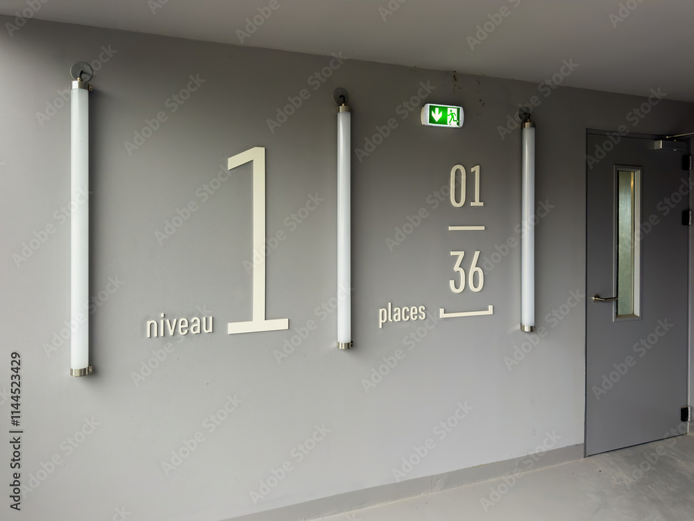Indoor parking lot signage on a gray wall indicating level one and ...