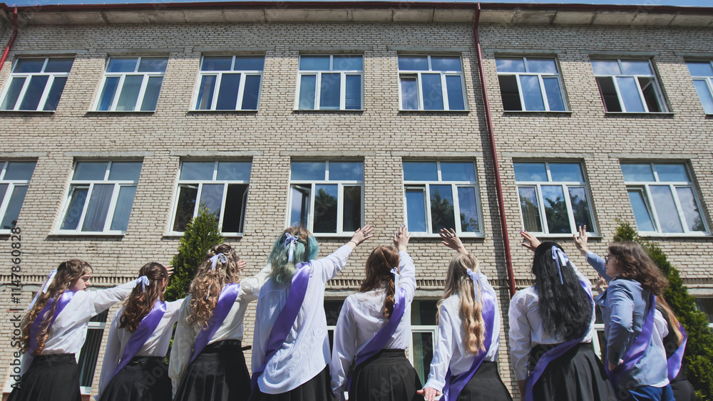 Group of graduating female students waving goodbye to their school ...