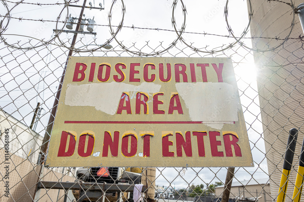 Sign stating Biosecurity Area Do Not Enter surrounded by barbed wire ...