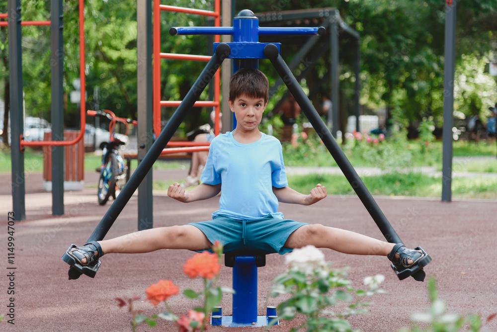 Happy boy doing sports on exercise machines on a summer playground ...