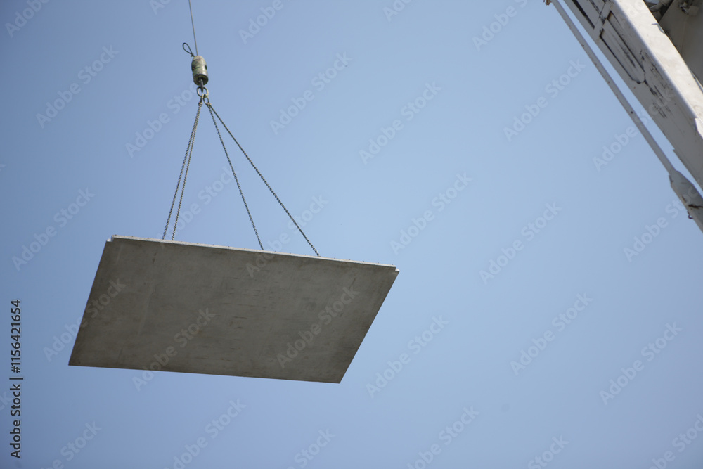 Construction site with crane lifting concrete slab on wire rope sling ...