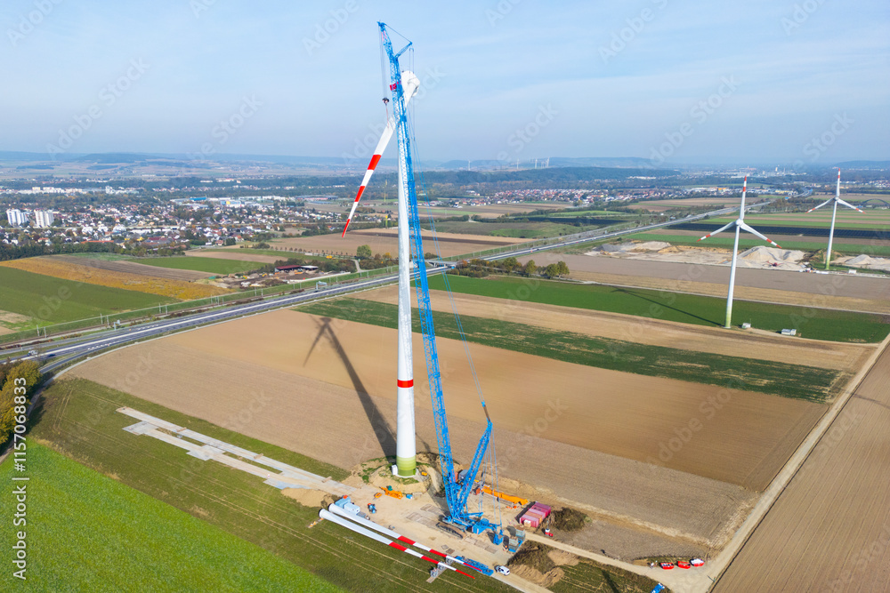 Wind power plant construction site. Massive crane is installing rotor ...