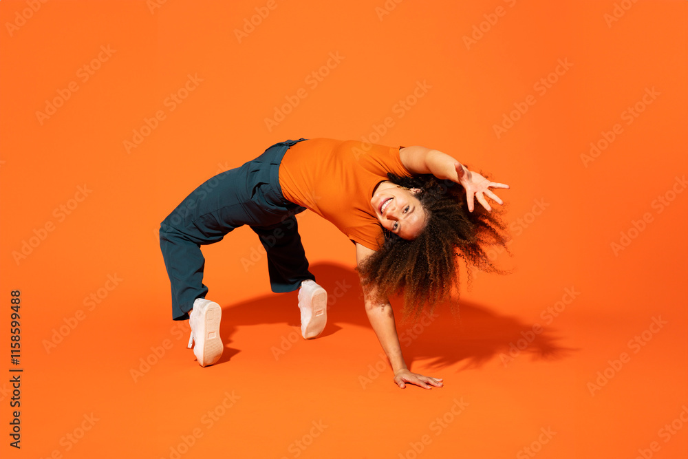 Happy woman bending over back in front of orange background Stock Photo ...