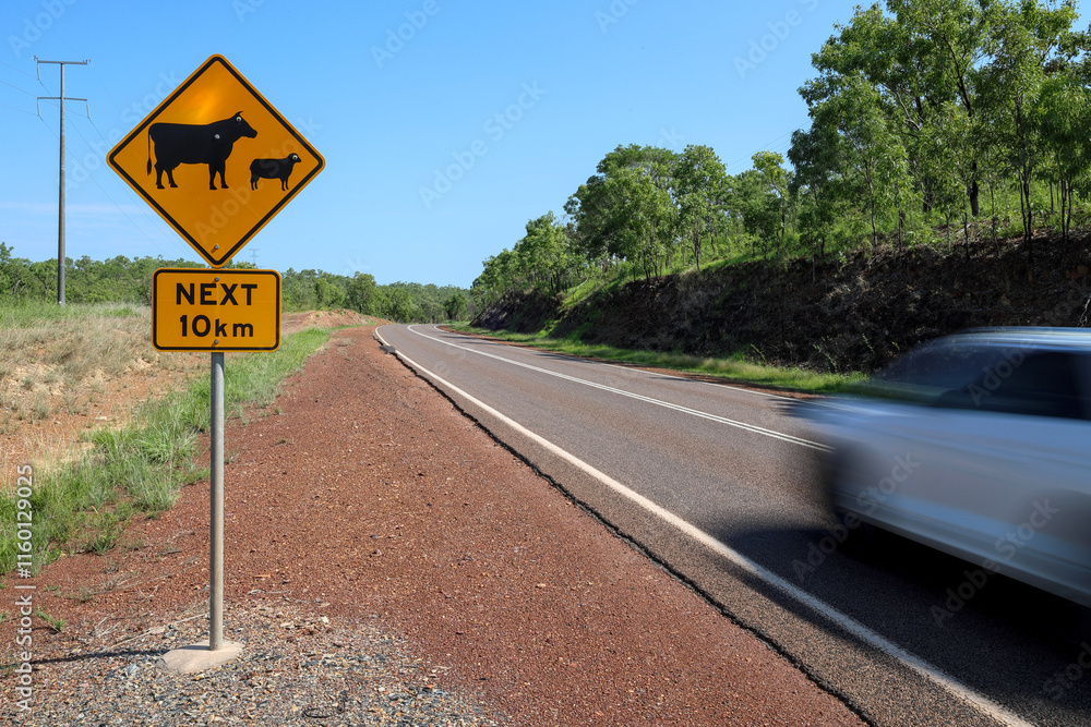 Road sign indicating animals on road, with speeding car ignoring danger ...