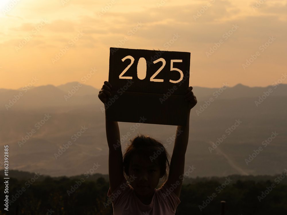 Silhouette of cute little girl holding 2025 sign on sunset background ...