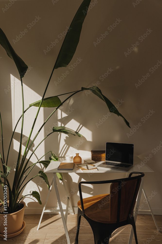 Organized home office setup with a laptop, paper and plant, capturing ...