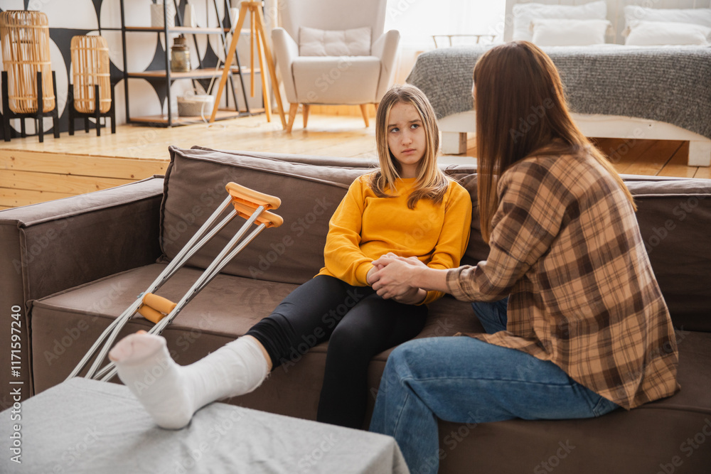 Girl with broken leg in cast sits with mother on couch at home. Sad ...