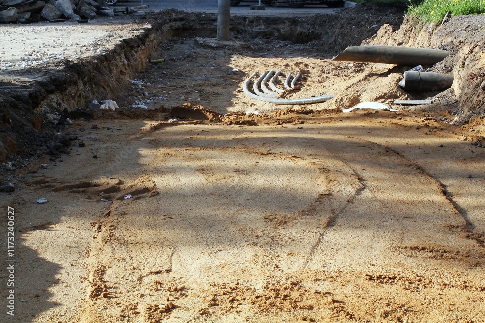 Dug trench on construction site with exposed soil, pipes and ...