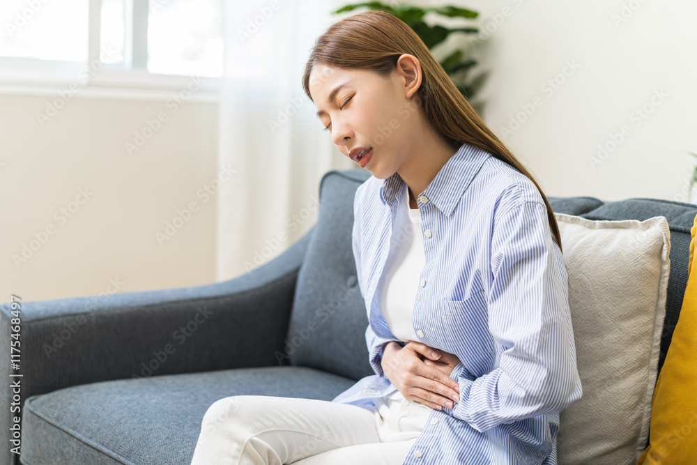 Sick asian young woman in pain, hand holding belly, stomach pain from food poisoning, girl hurt ...
