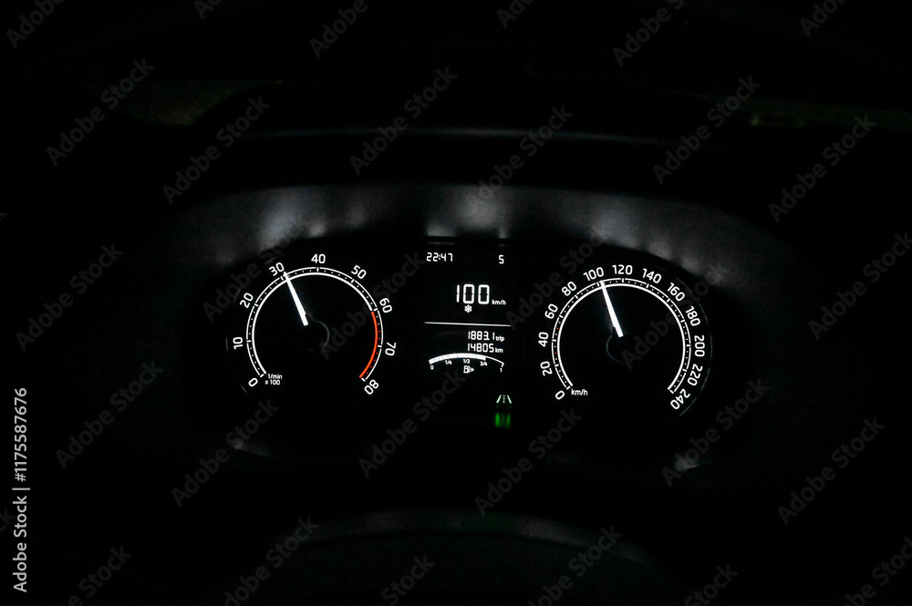 Modern dashboard in the car at night. Illuminated tach and speed gauges ...