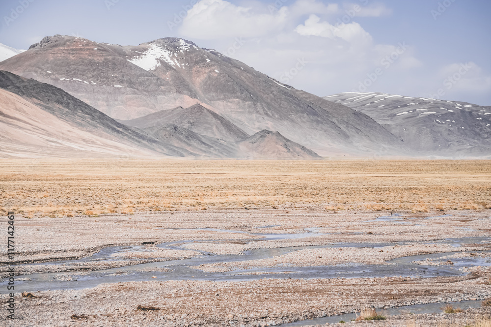 High-mountain river flows in a valley against the background of rocky ...