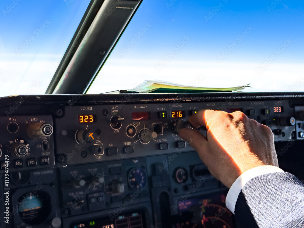 Pilot setting or adjusting autopilot in passenger airplane in flight ...