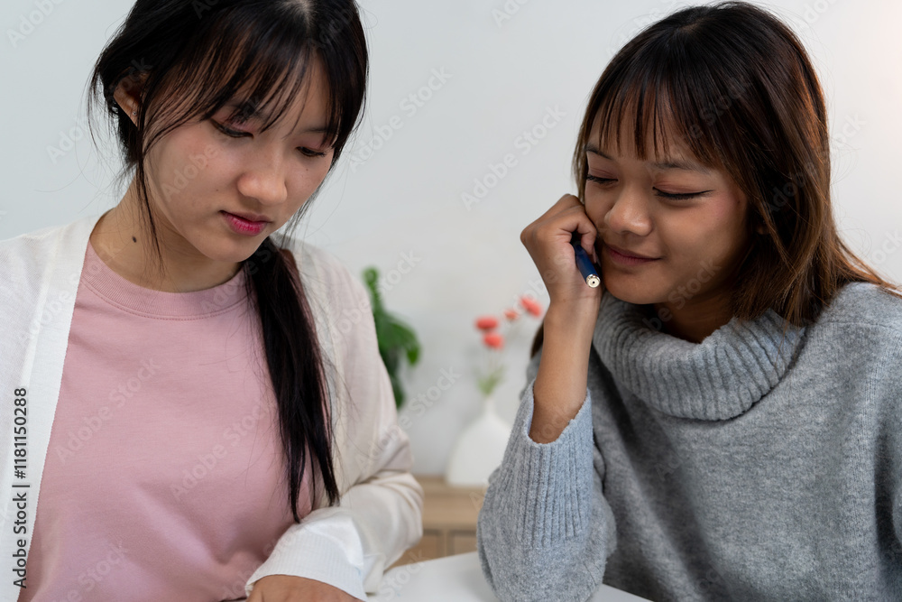 Female higher education student using laptop and studying book in home ...