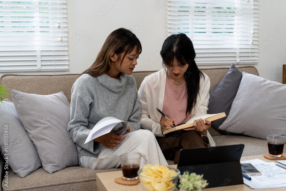 Female higher education student using laptop and studying book in home ...