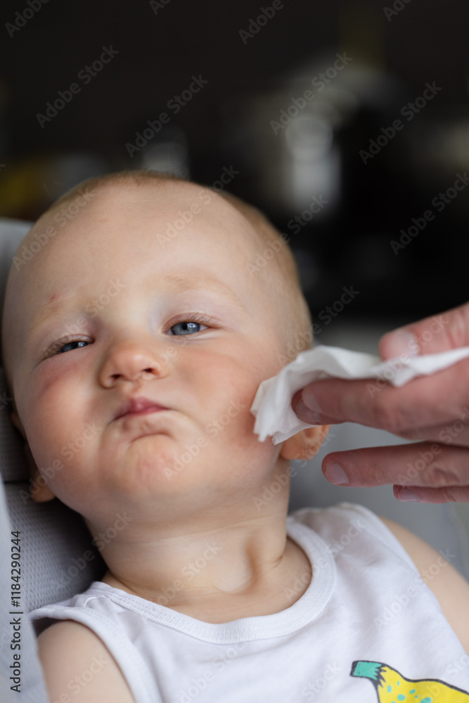 Little child does not want to wipe his face with a tissue after meal ...