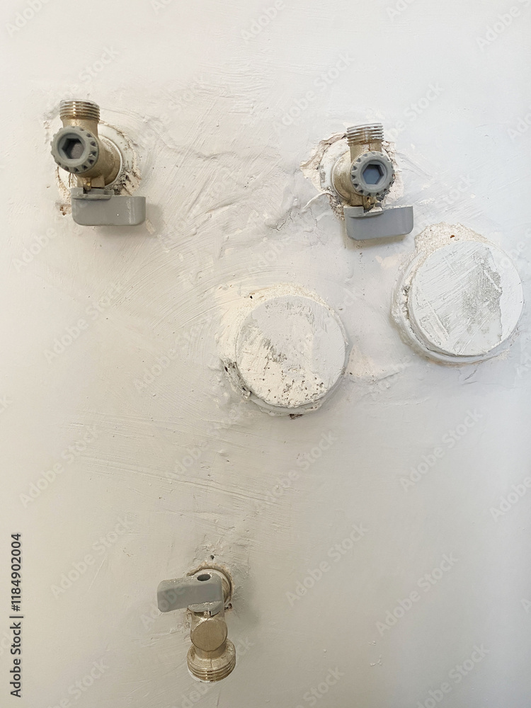 Plumbing Valves and Caps on White Wall. Close-up of plumbing valves and ...