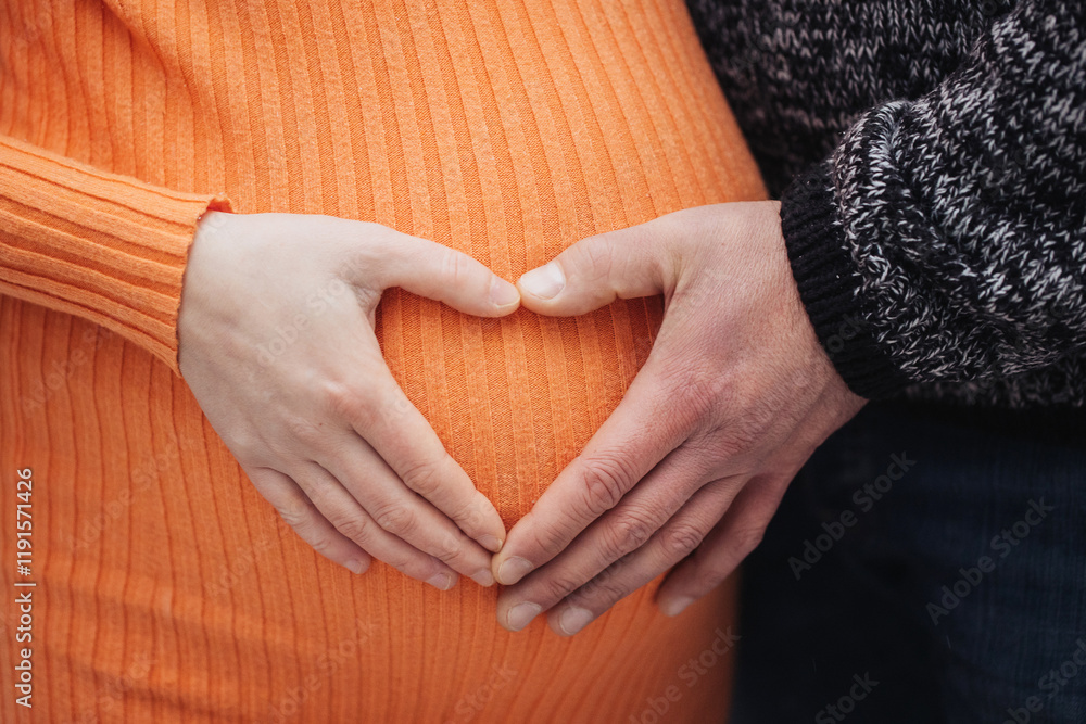 Pregnancy photo session. Heart shape made by couple hands on baby bump ...