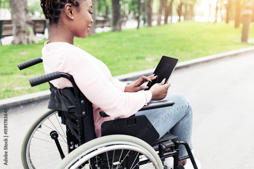 Young black woman in wheelchair using tablet computer with empty screen ...