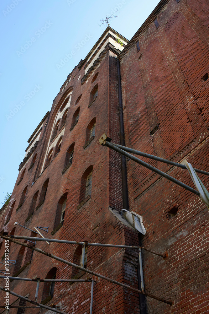 Upward view of a tall, abandoned aged brick building with multiple ...