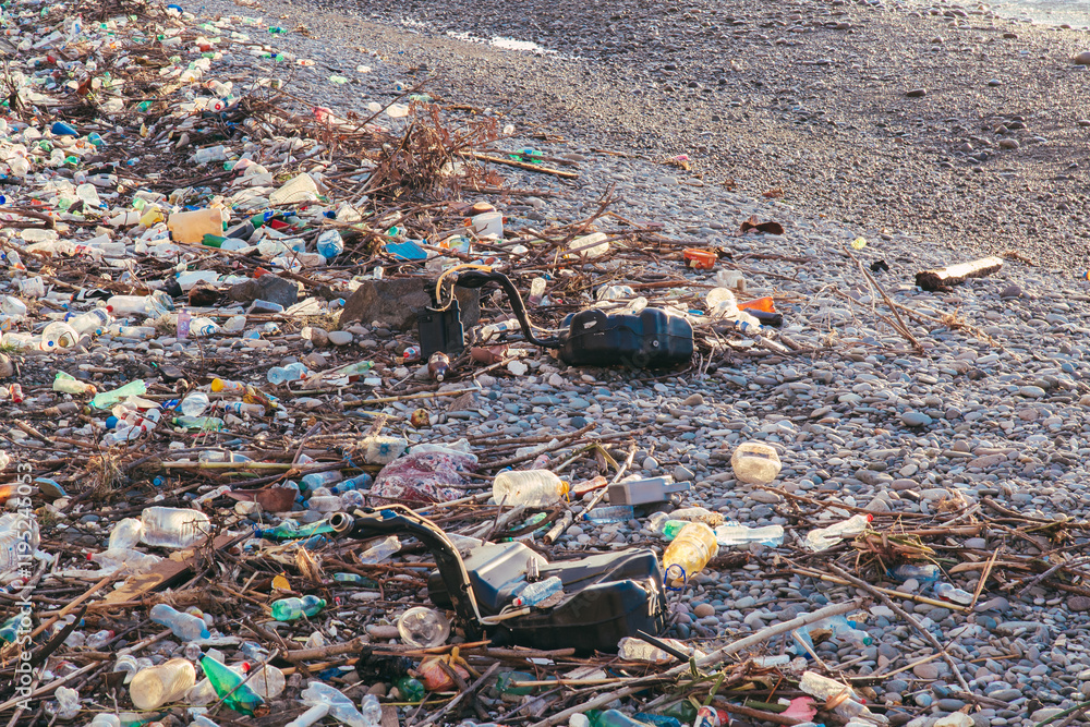 Polluted beach covered with plastic waste, bottles, and debris washed ...