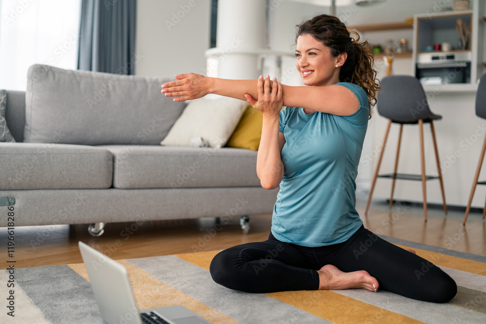 Mid adult Caucasian woman in athletic attire follows yoga instruction ...