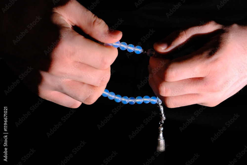 Close-up hands holding rosary beads on a black background. Ramadan ...