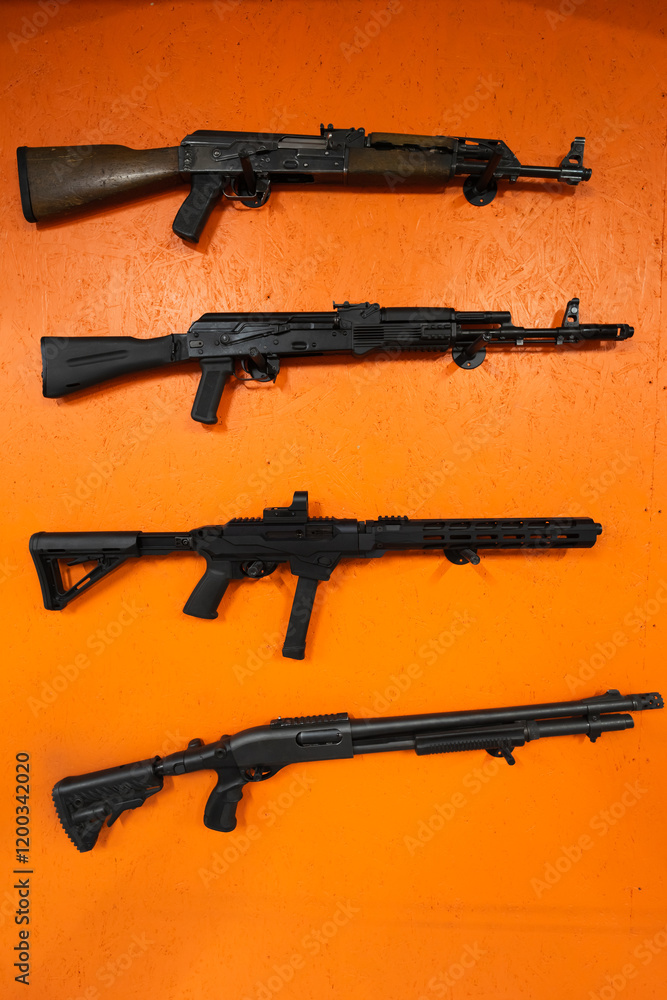 Various weapons hang on the orange wall in the shooting range, rifles ...