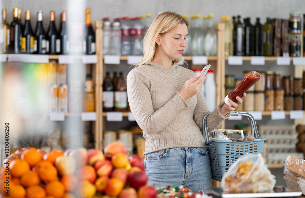Young woman buyer scanning qr code for tomato ketchup sauce in grocery ...