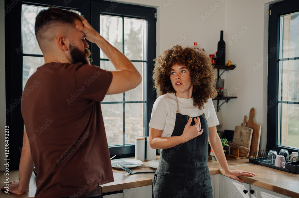 Young couple arguing in kitchen, woman explaining with hand gestures ...