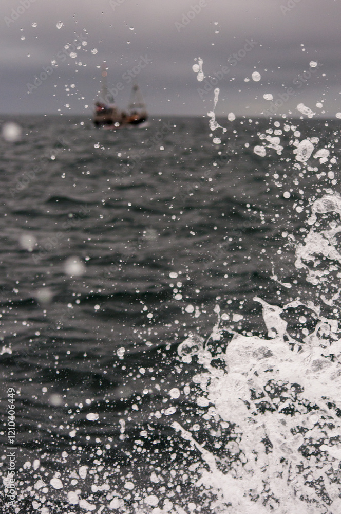 fishing boat is navigating choppy waters, creating a spray of water ...