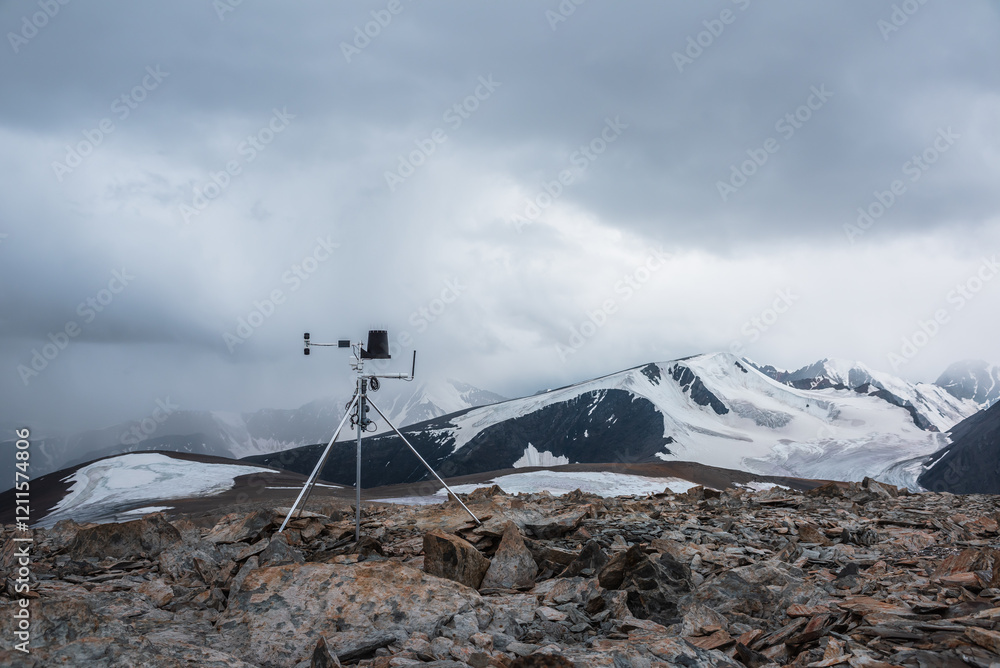 Automatic meteorological station on stone hill with view to large snow ...