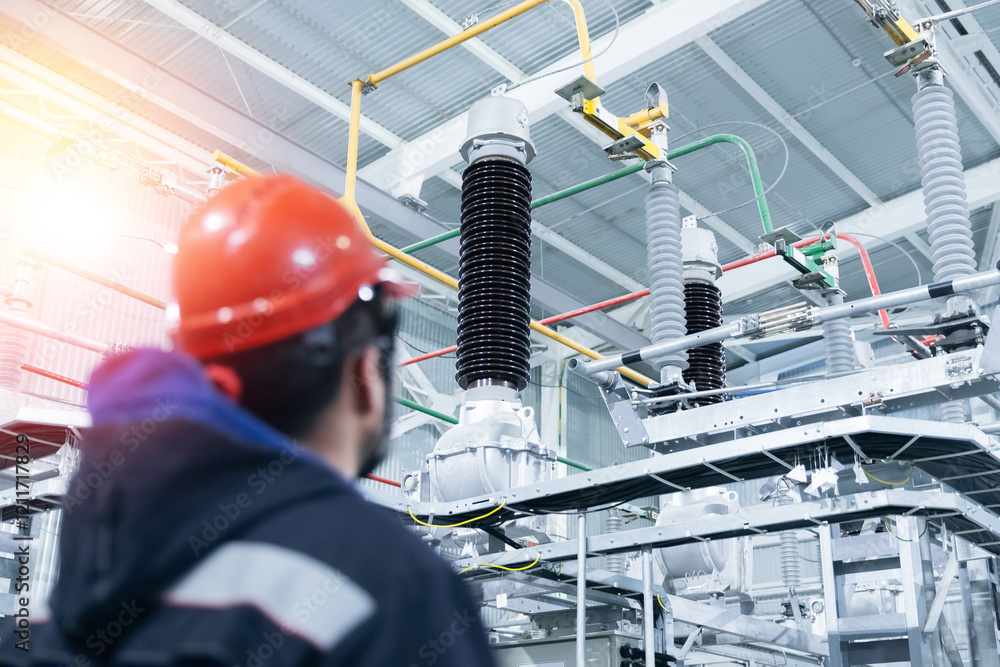 Electrical engineer worker inspects electrical substation with high voltage switches, wires ...