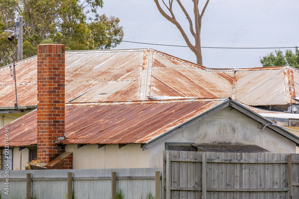 An old, weathered house with a rusty corrugated iron roof and a red ...