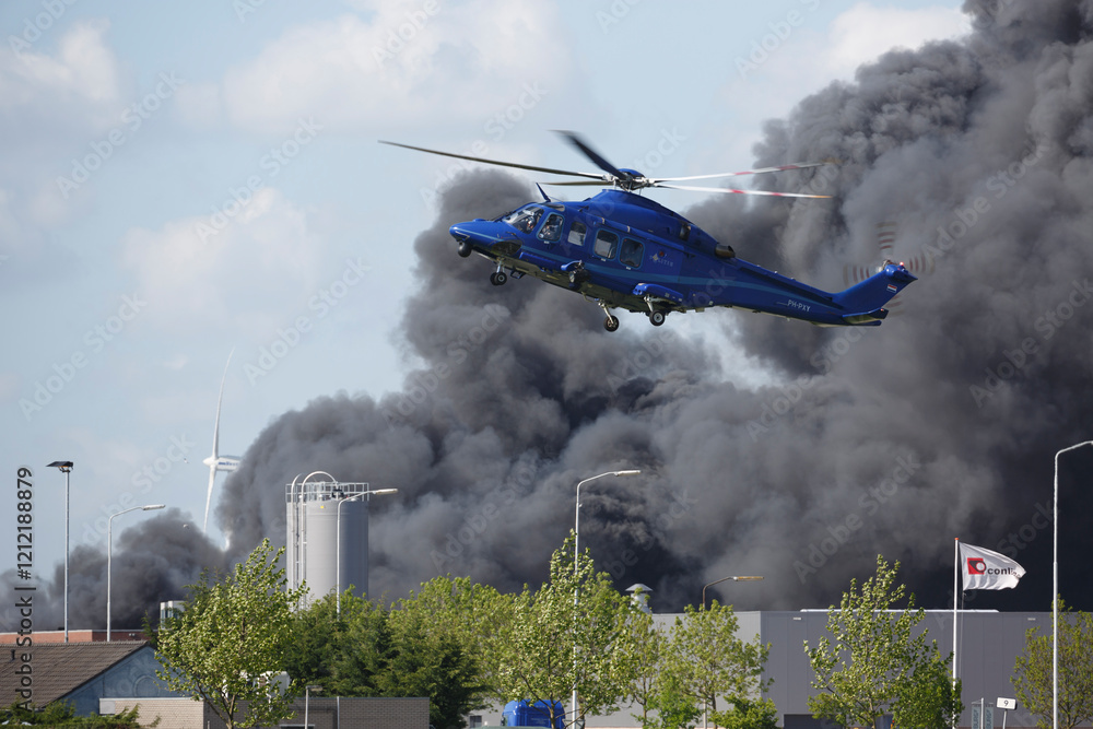 Heavy smoke rising from industrial fire as helicopter takes flight for ...