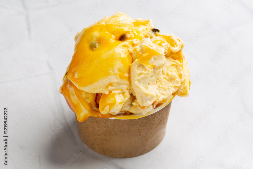 Passion fruit ice cream melting, dripping over brown cardboard cup edge ...
