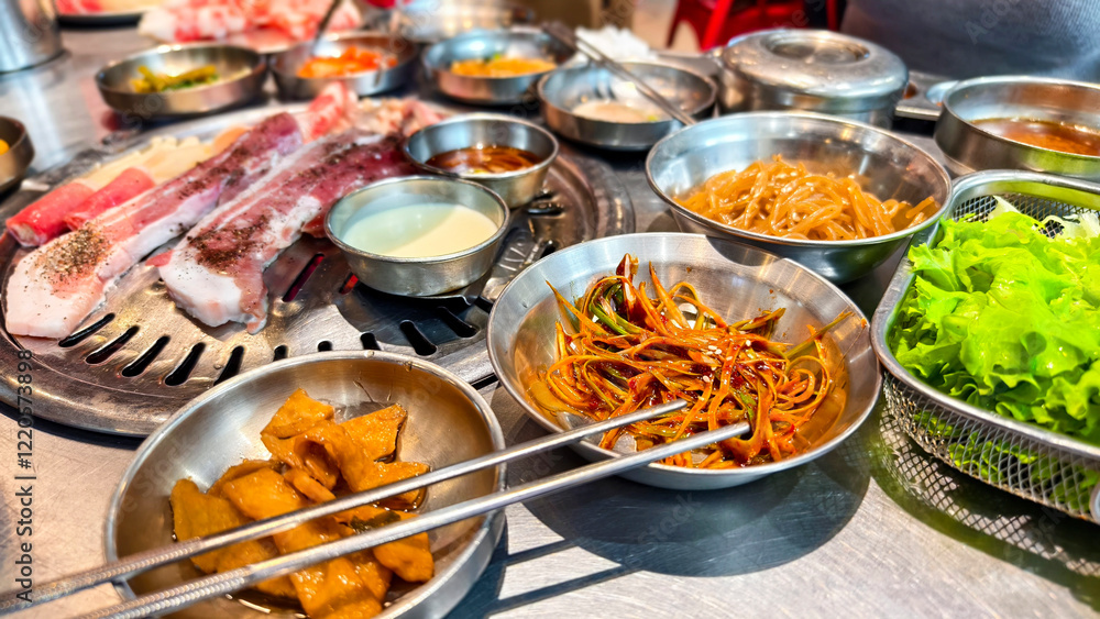 Samgyeopsal grill setup with multiple side dishes in a Korean ...