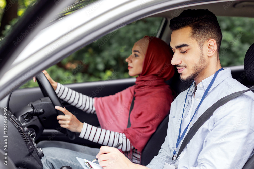 Serious millennial arab man taking driving test from woman in hijab ...