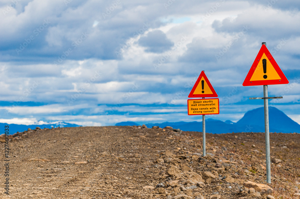 Warning signs indicate hazardous road conditions in a remote area with ...