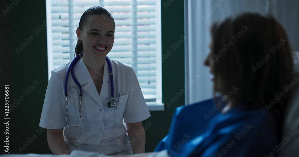 Doctor beside elderly patient in hospital room, presenting paperwork ...