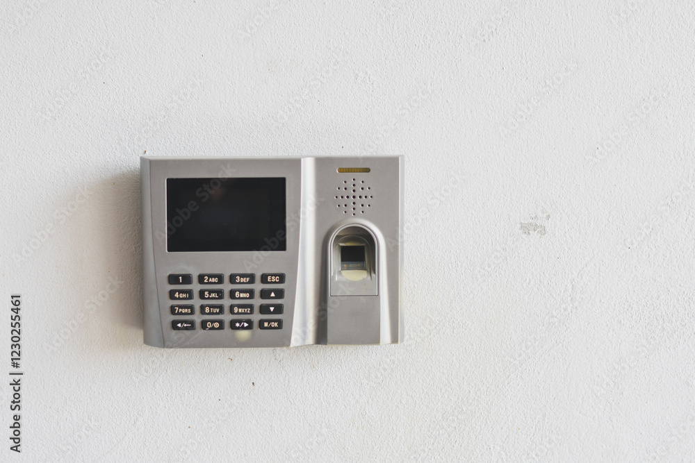 biometric time attendance device mounted on a wall. The device has a ...