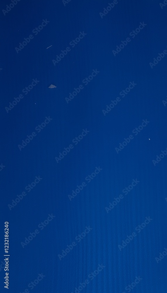 Deep blue sky with a faint distant object or two, minimalist style and ...