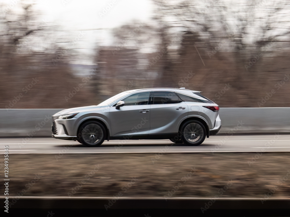 Fast moving Lexus RX 450h+ on the city road. Gray SUV driving on ...