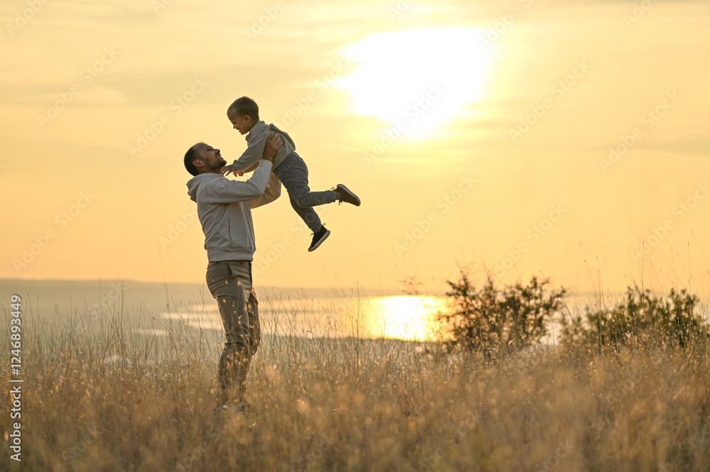 Father holding his young son in his arms at sunset outdoors. Warm ...