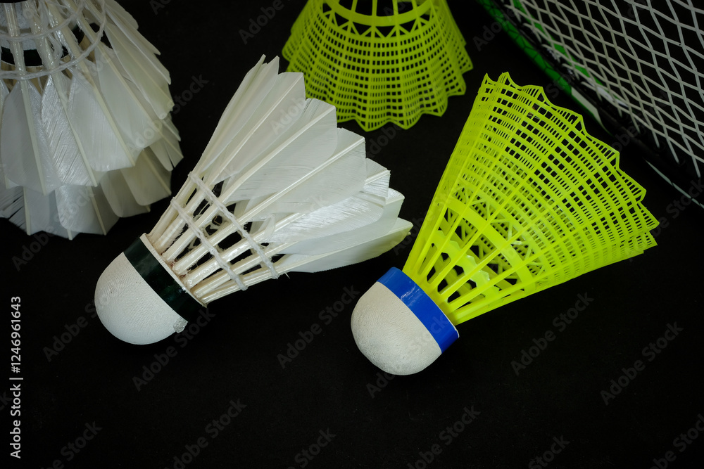 Badminton shuttles, both feathered and plastic, lying on a black ...