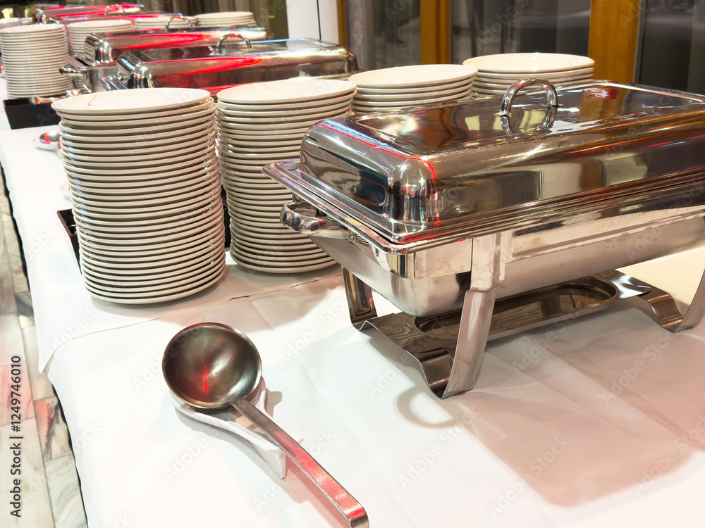Buffet setup with chafing dishes and stacks of plates ready for ...