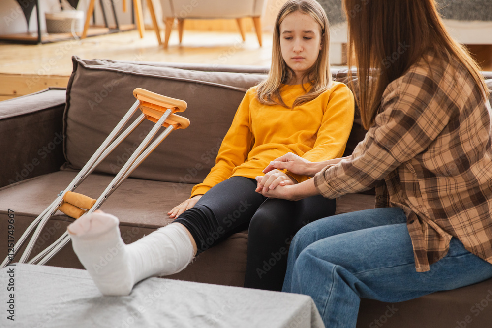 Girl with broken leg in cast sits with mother on couch at home. Sad ...