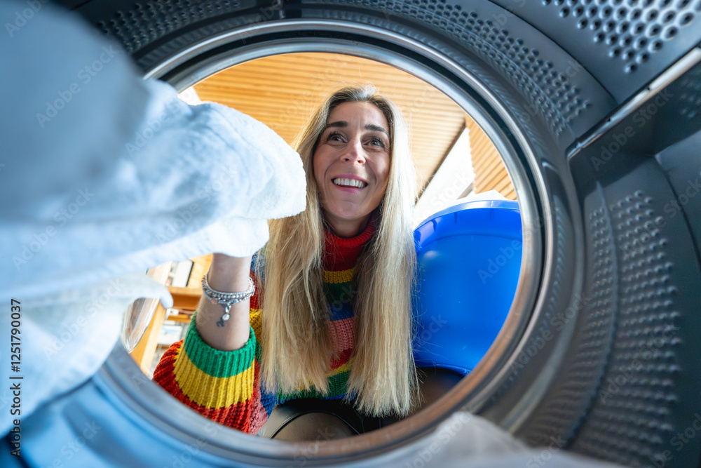 Young woman folding freshly washed clothes in a self-service laundromat ...