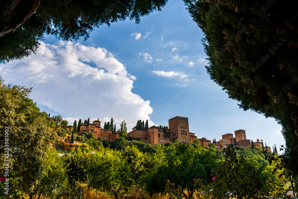 Alhambra Palace in Granada framed by orchard trees and cypress from a ...