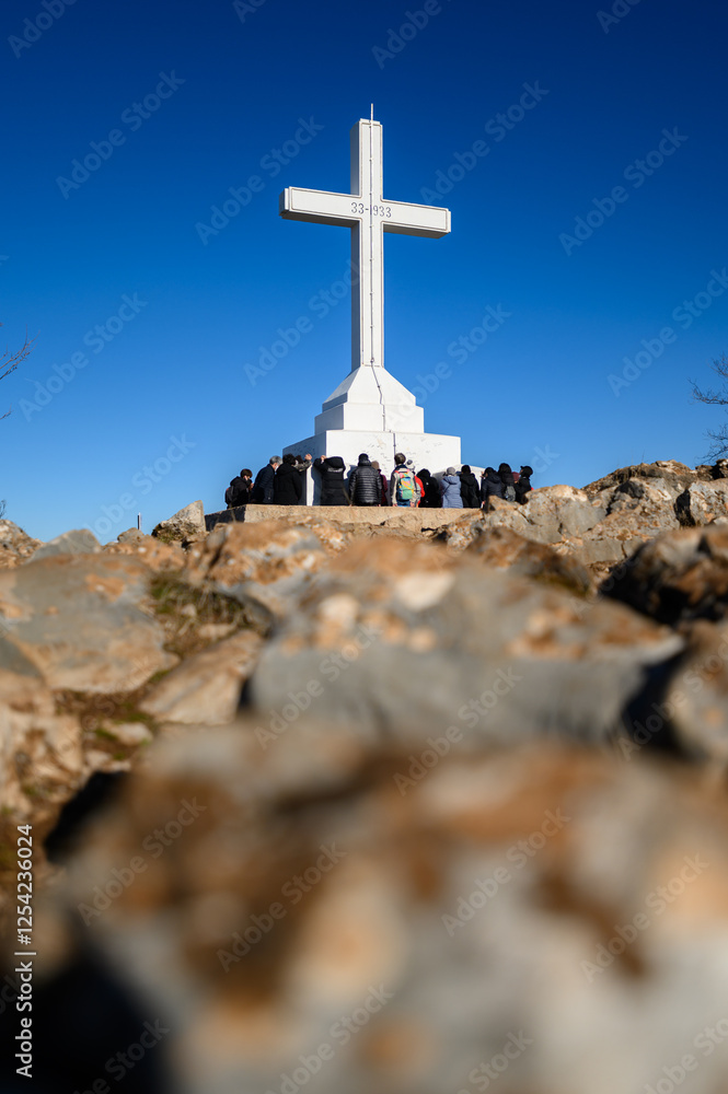 Pilgrims praying around the white cross on the top of Mount Križevac ...